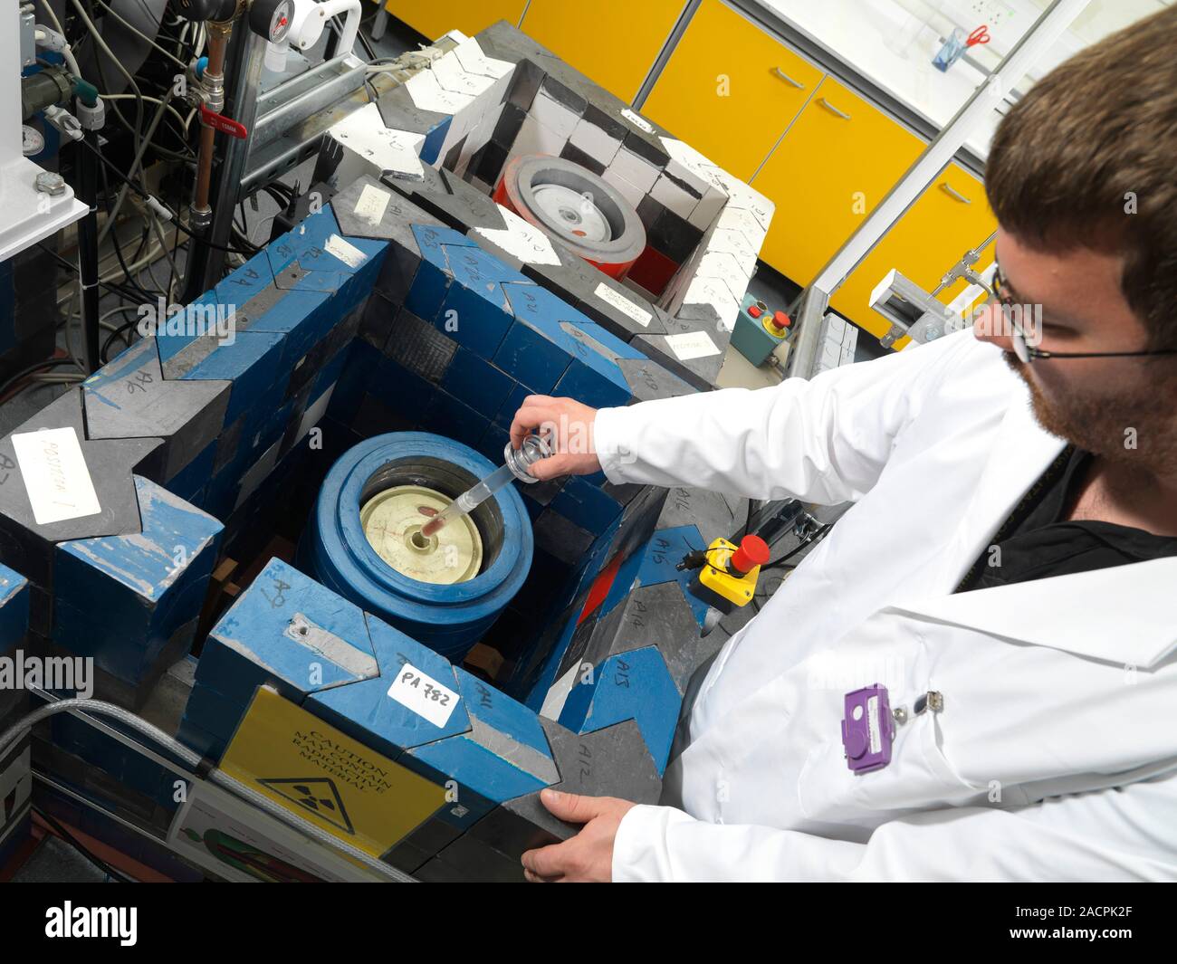 Ionisation chamber system. Technician loading a sample into a secondary ...