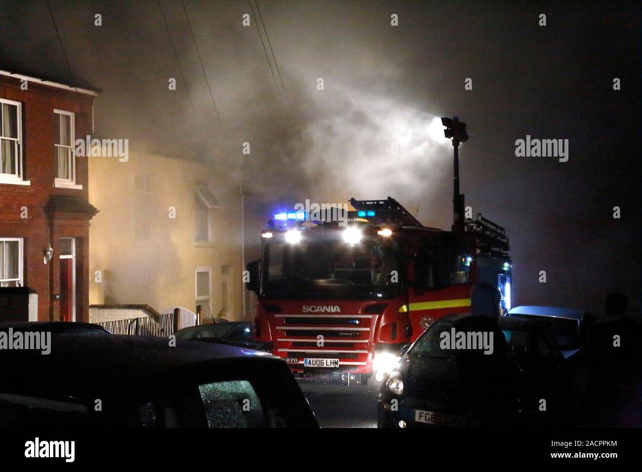 Fire engine attending a house fire at night. The fire, thought to have ...