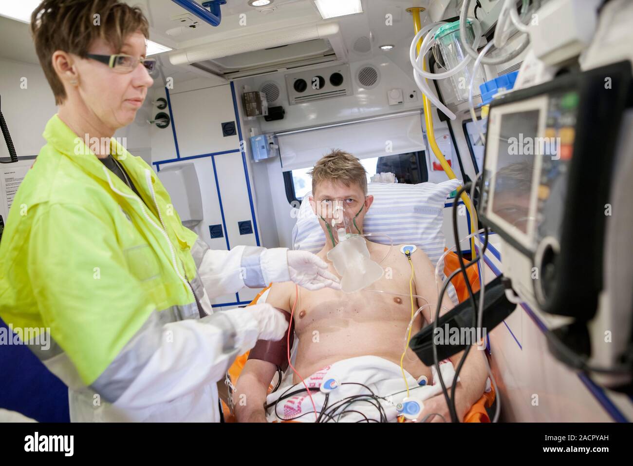 Cardiac patient in an ambulance. Paramedic preparing to perform an ...