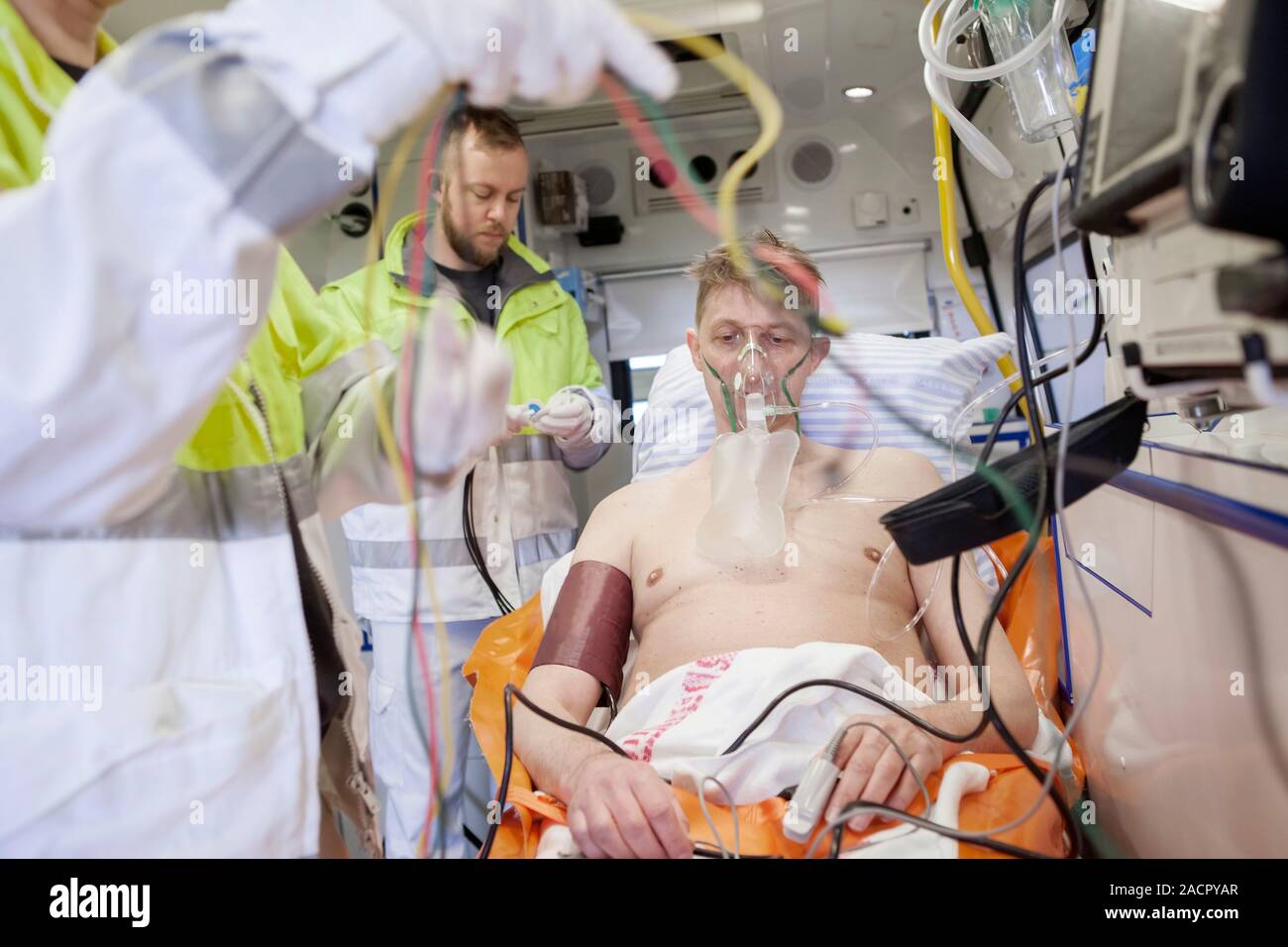 Cardiac patient in an ambulance. Paramedic preparing to perform an ...