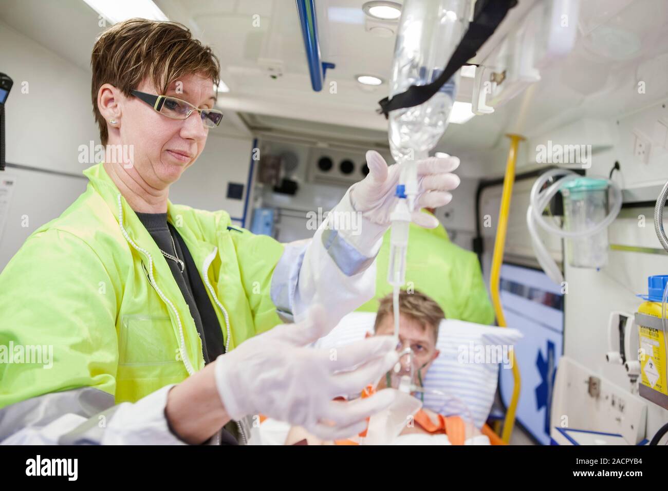 Cardiac patient in an ambulance. Paramedic preparing an intravenous (IV ...