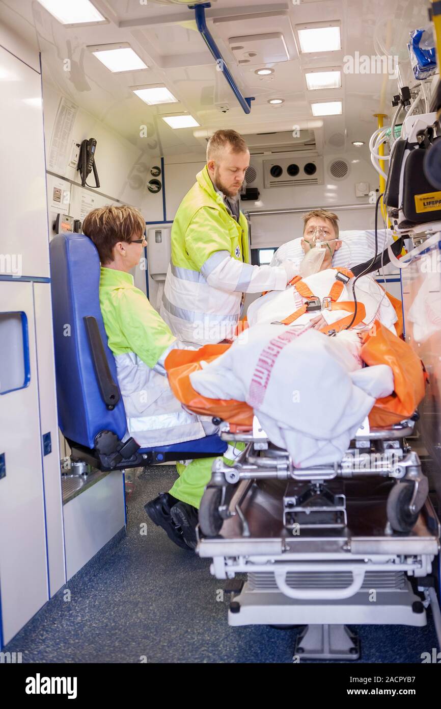 Cardiac patient in an ambulance. Paramedics attending to a 50-year-old ...