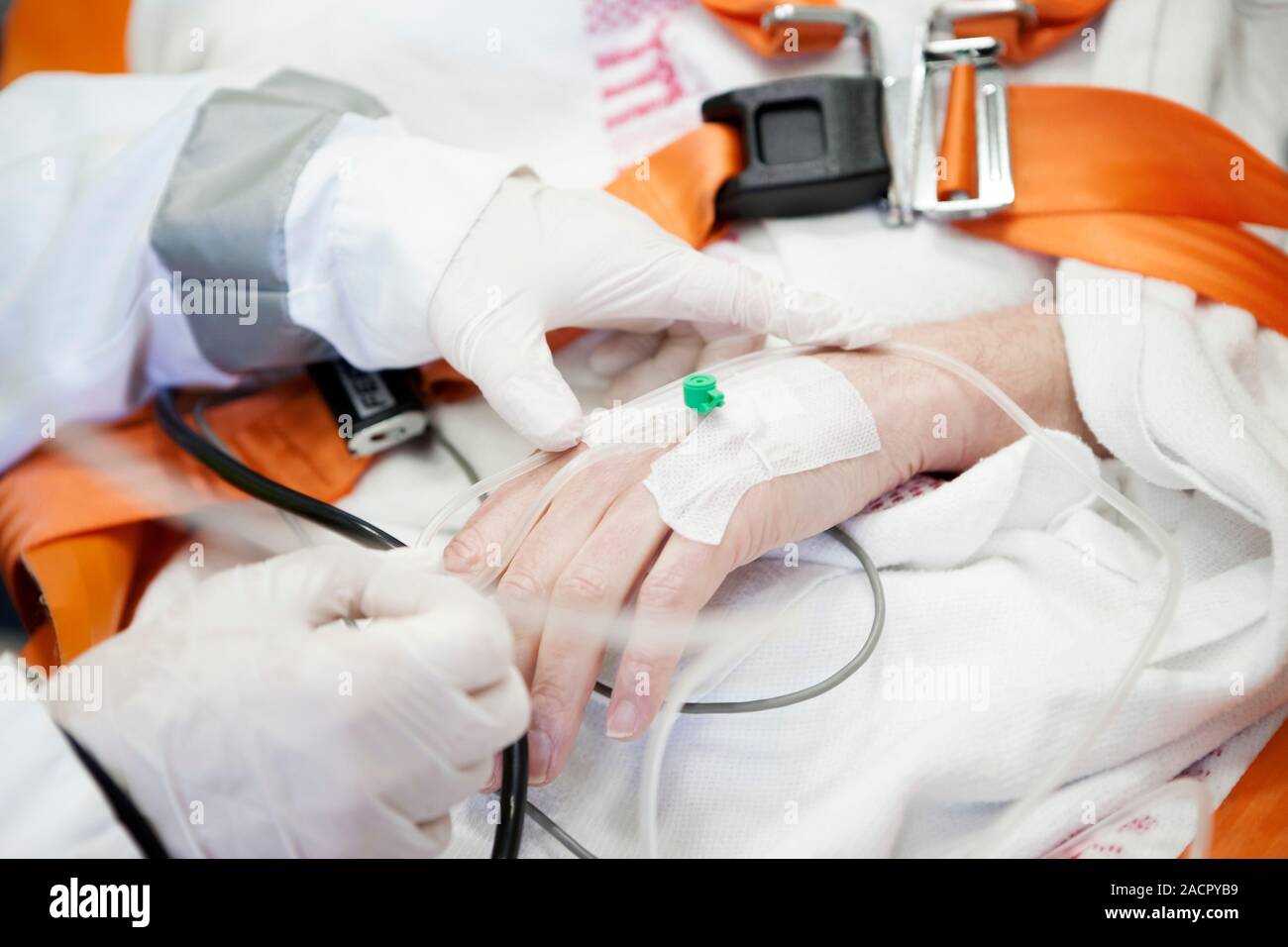 Cardiac patient in an ambulance. Paramedic preparing an intravenous (IV ...