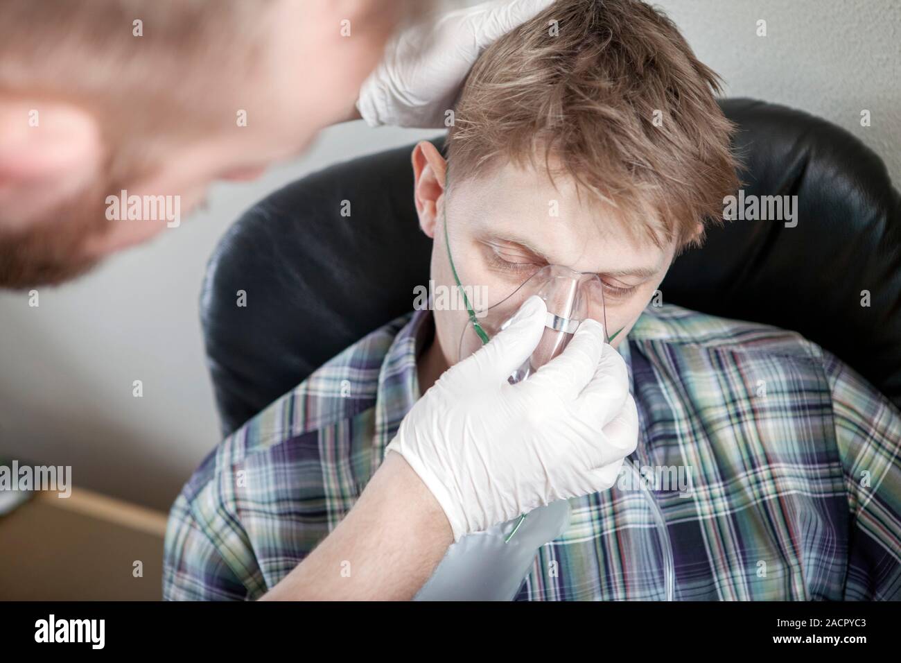 Stroke patient. Paramedic administering oxygen to a 50-year-old stroke ...