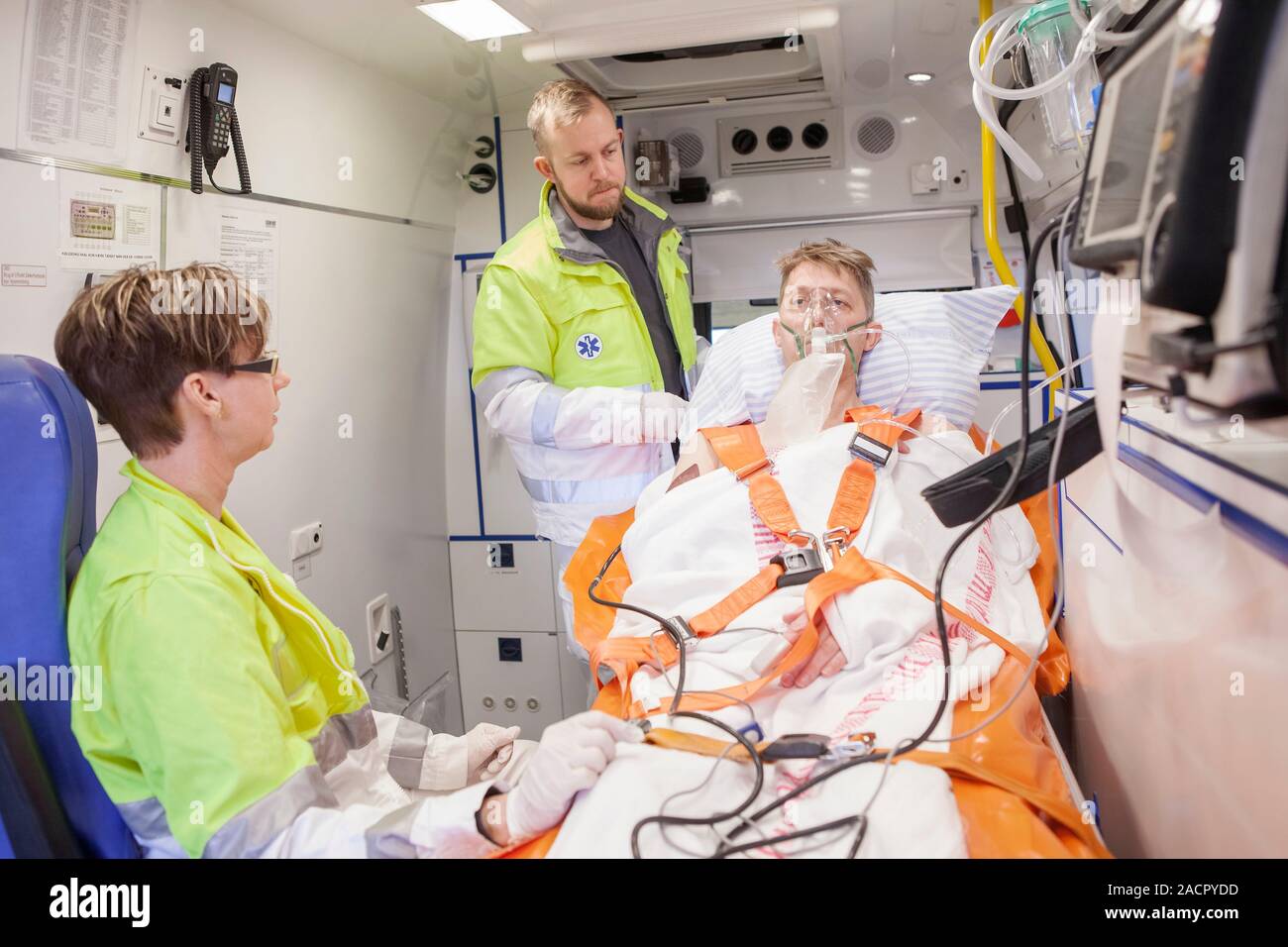 Cardiac patient in an ambulance. Paramedics attending to a 50-year-old ...