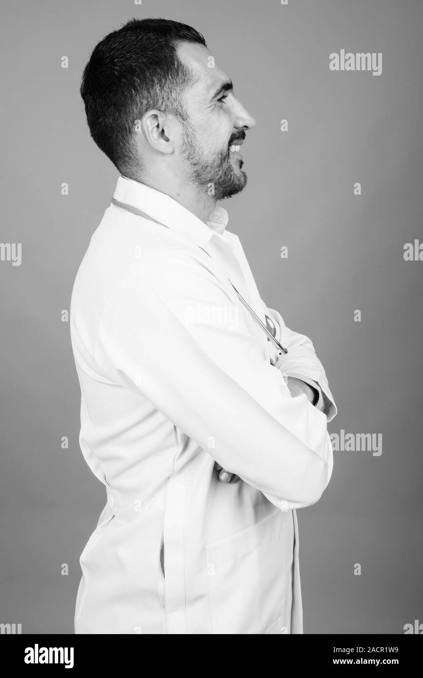 Handsome bearded Persian man doctor against gray background Stock Photo ...