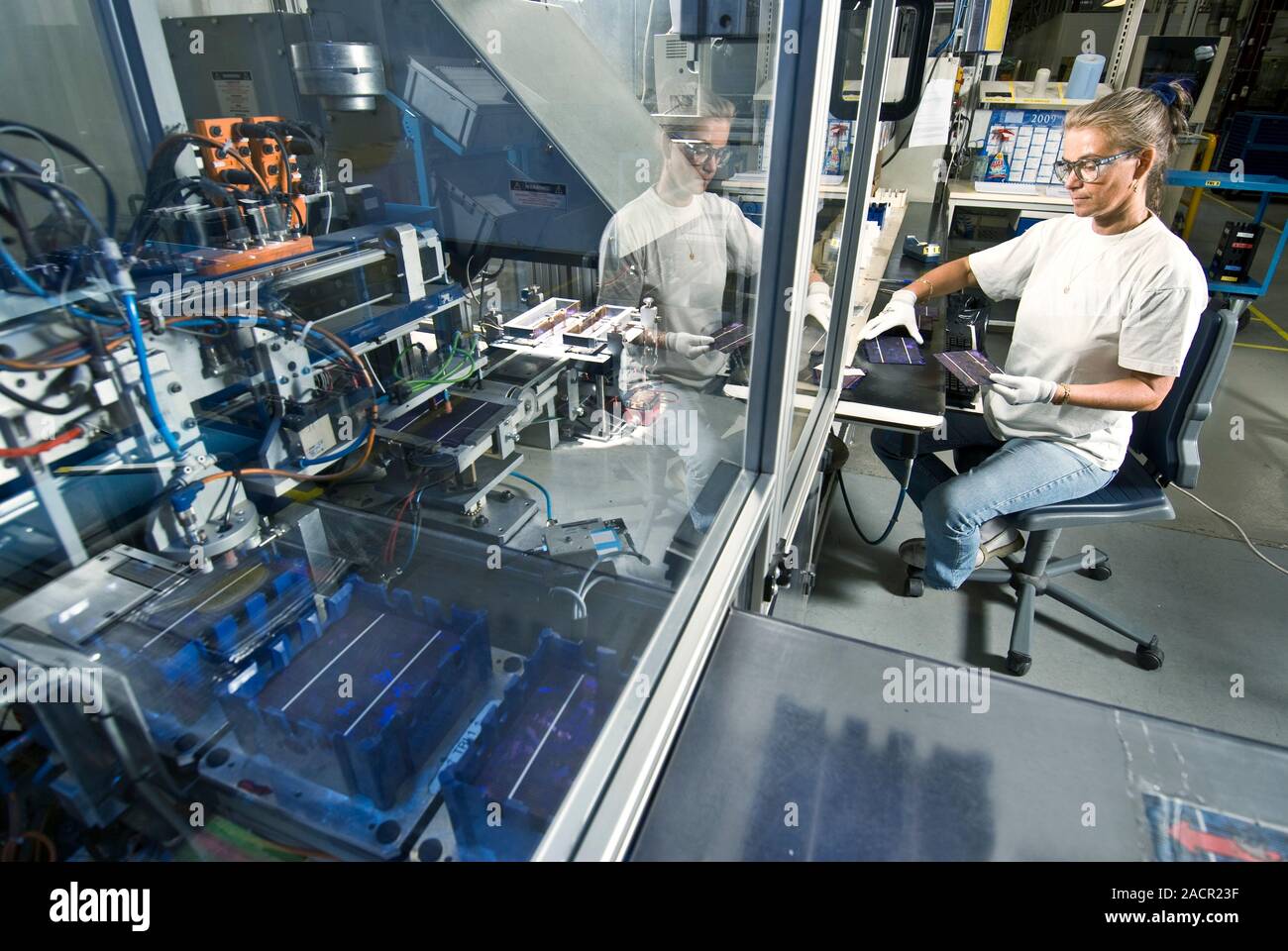 Manufacturing solar panels. Worker testing solar cells (photovoltaic ...