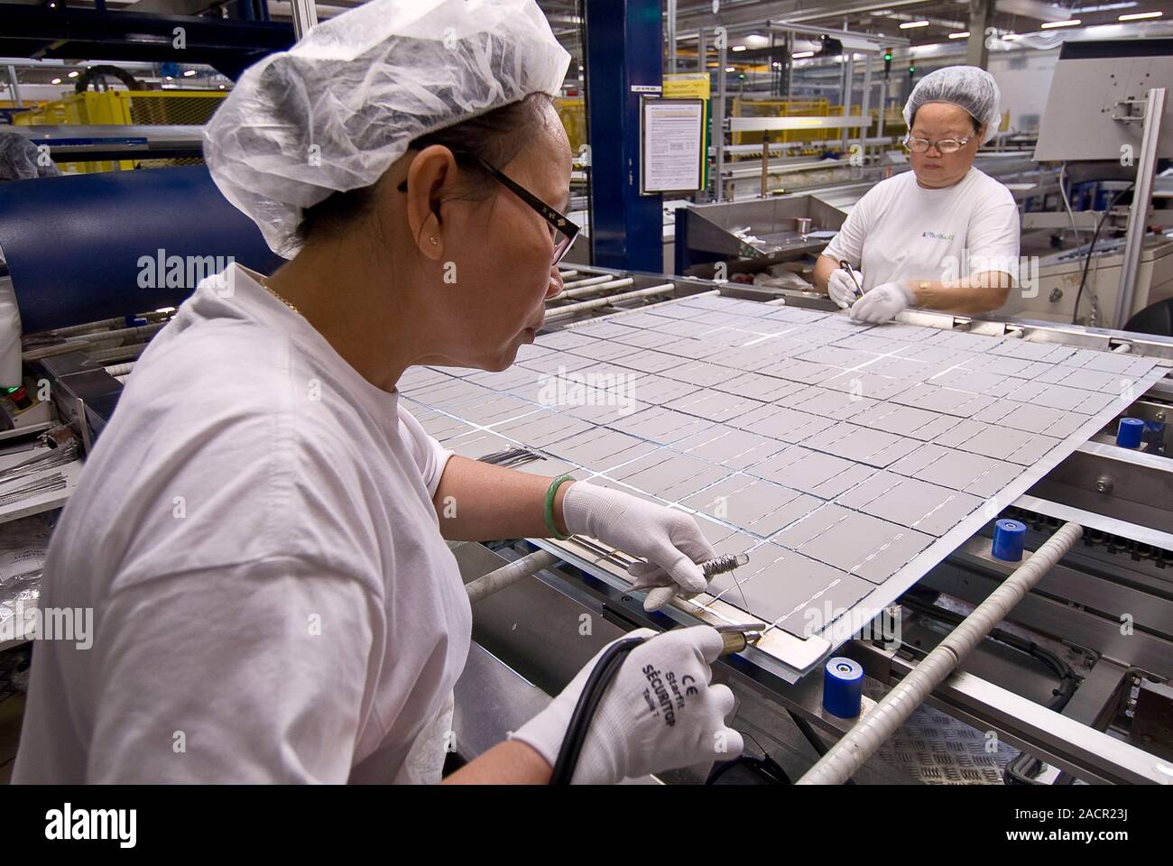 Manufacturing solar panels. Factory workers assembling solar cells ...