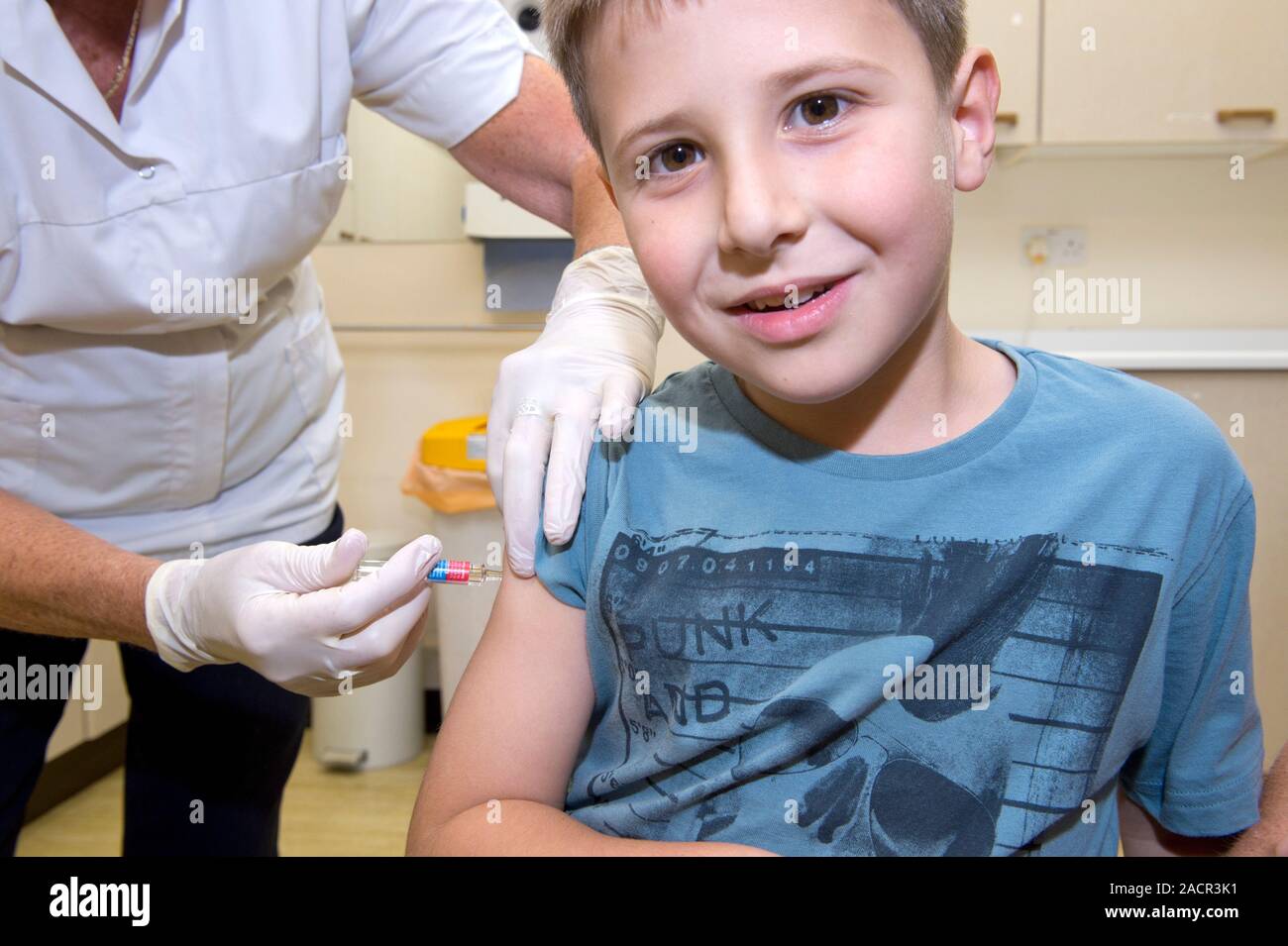 Nurse injecting flu (influenza) vaccine into the arm of a young male ...