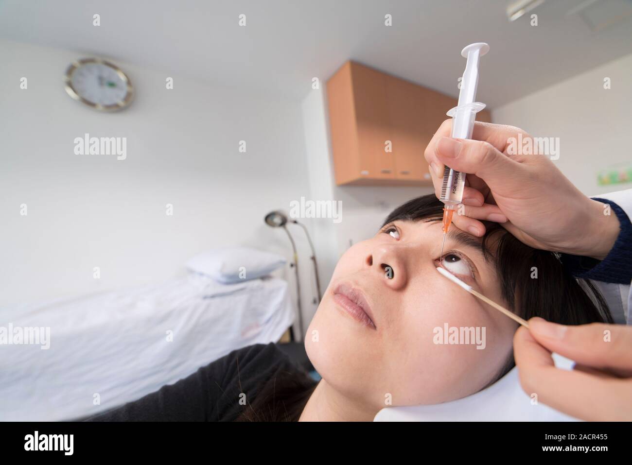 Clearing tear ducts. Ophthalmologist using a syringe to flush out the ...