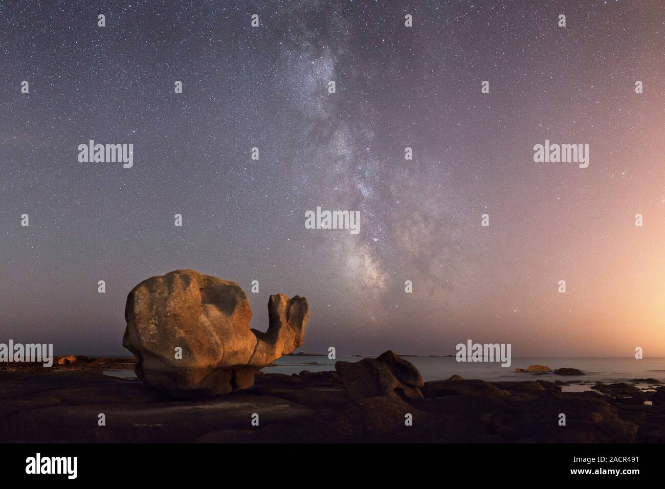 Coastal rock under the Milky Way. Twilight lit rocks on the shore under ...