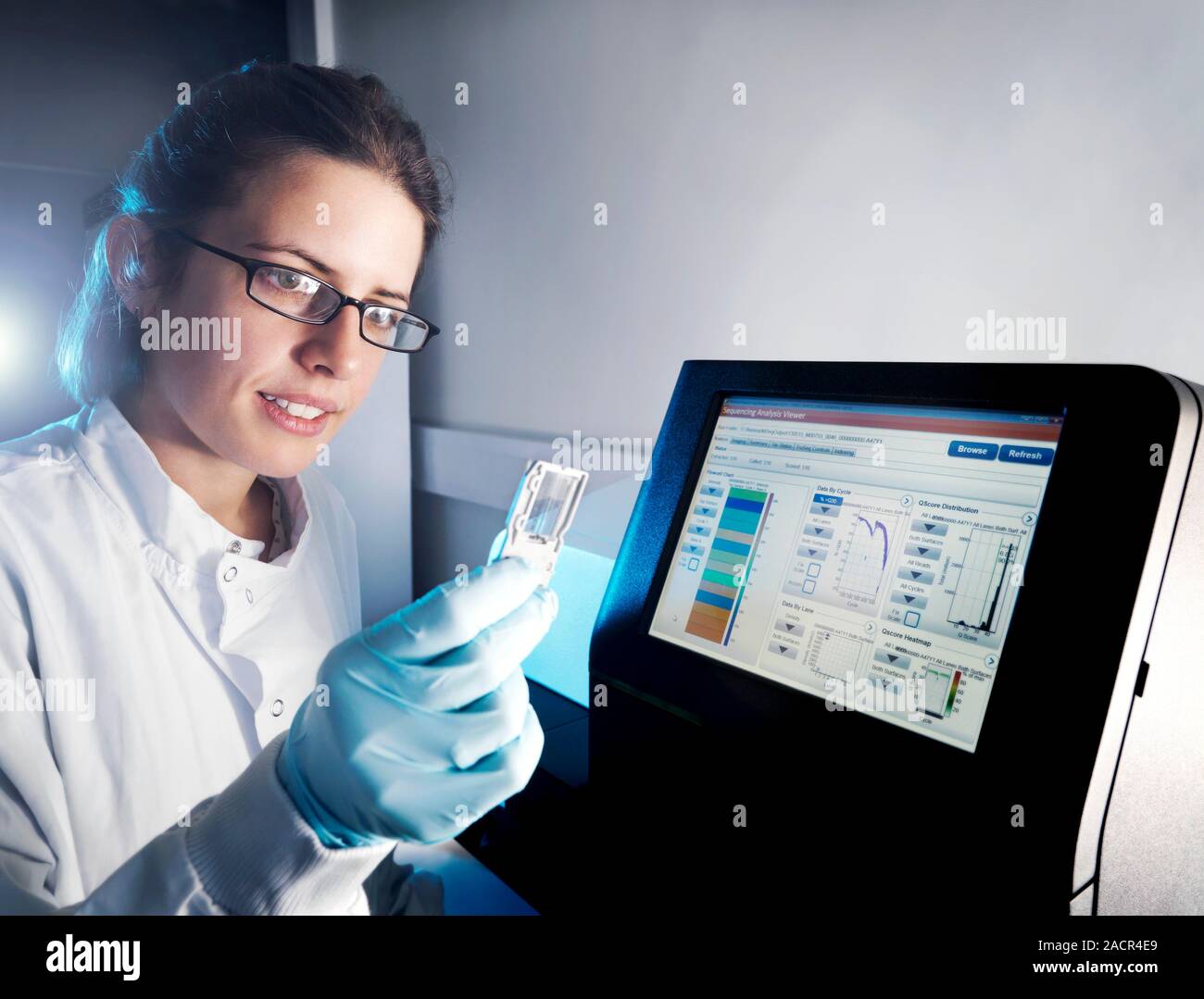 DNA sequencing. Researcher examining a flow cell from a benchtop high ...