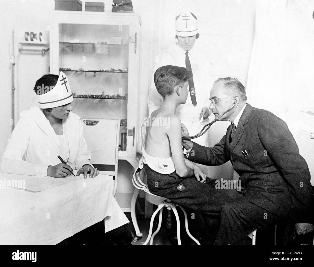 Tuberculosis campaign, early 20th century. Doctor using a stethoscope ...