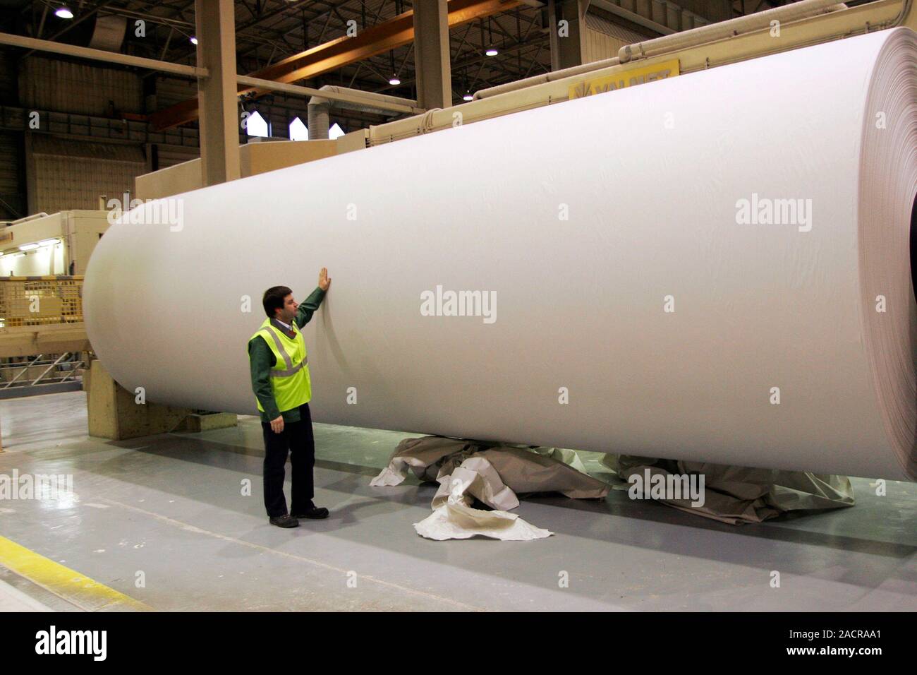 Paper mill. Worker examining a paper roll at the Chapelle Darblay paper ...