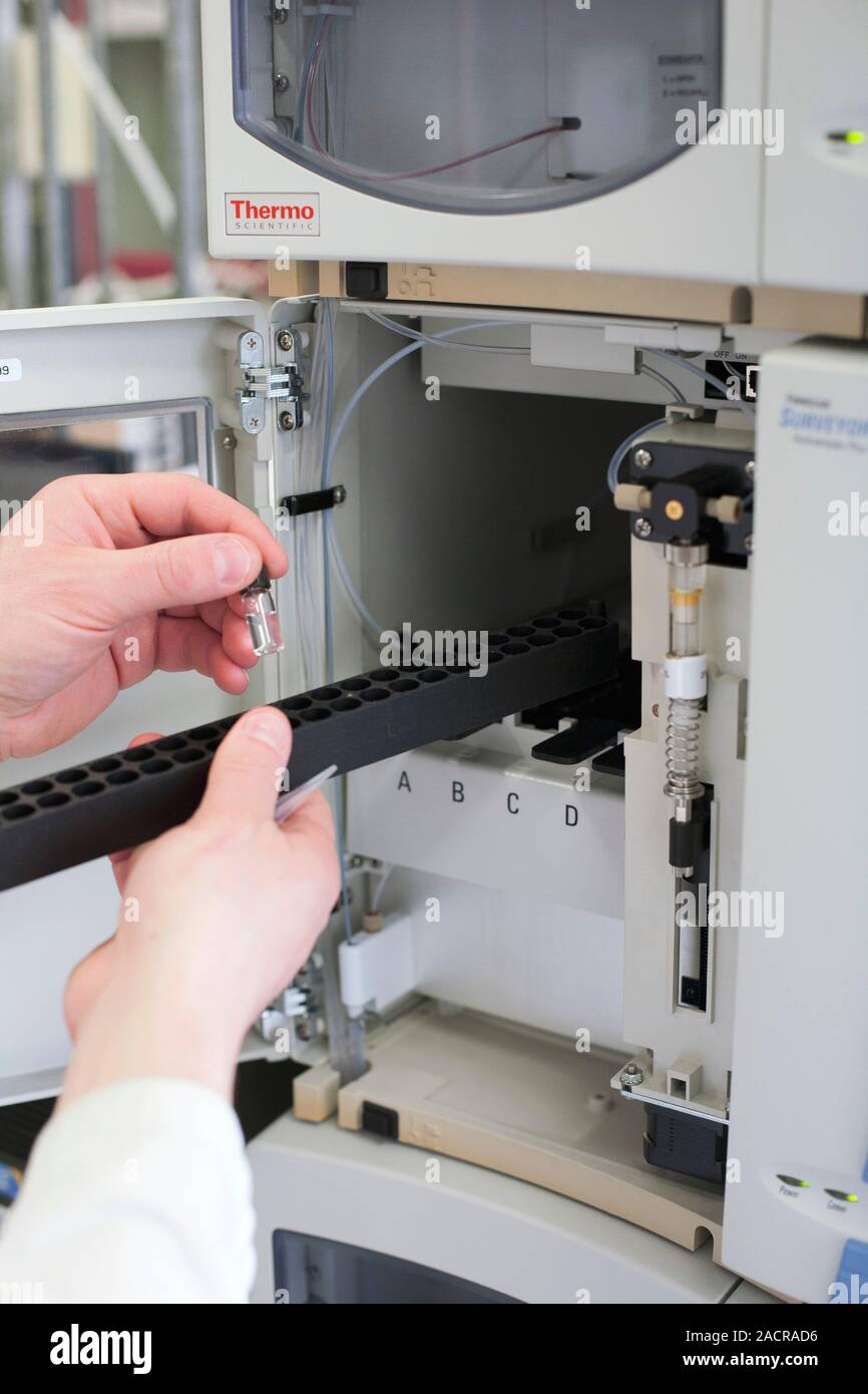 Bio-organic chemistry lab. Scientist loading a sample into a machine in ...