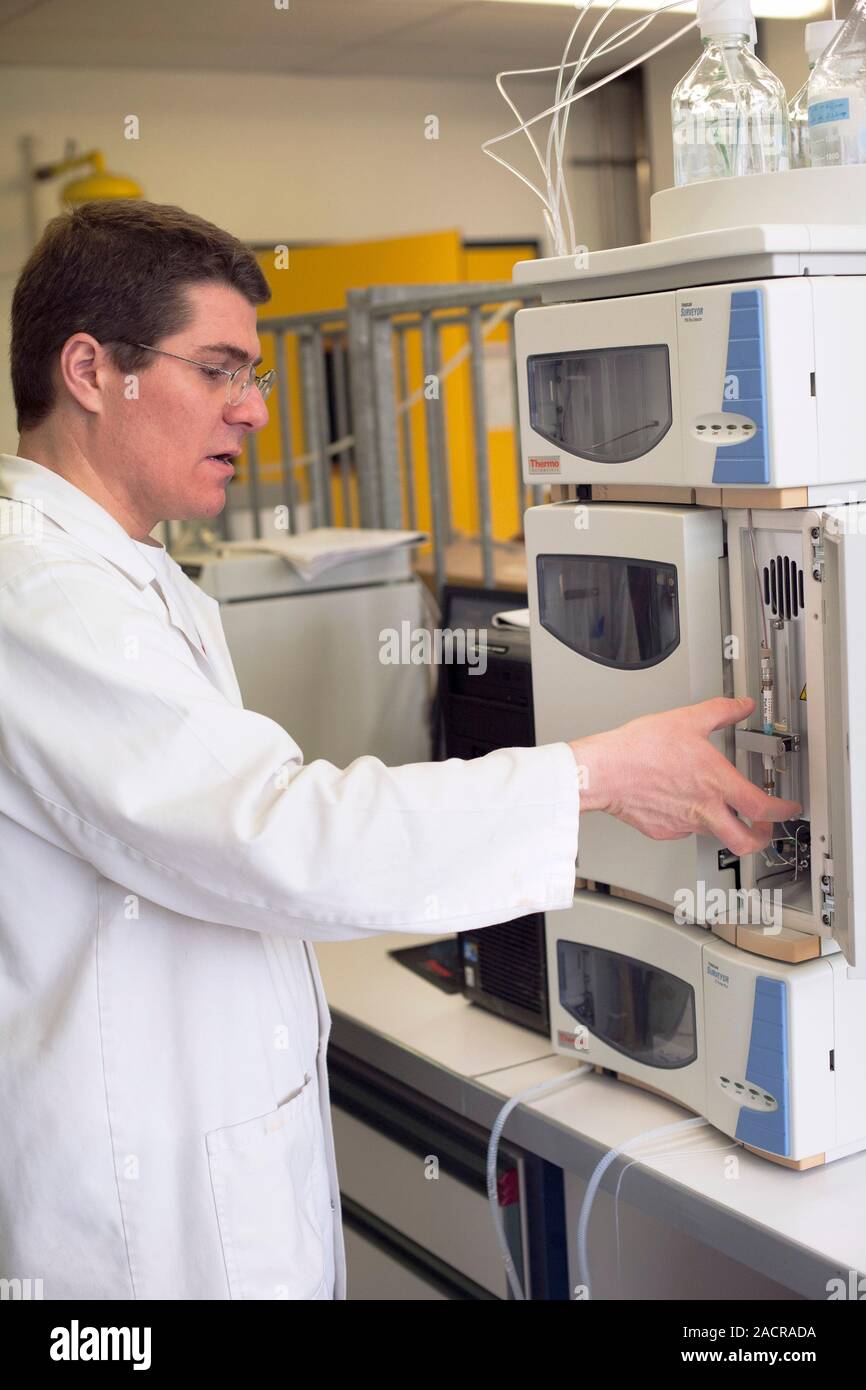 Bio-organic chemistry lab. Scientist loading a sample into a machine in ...