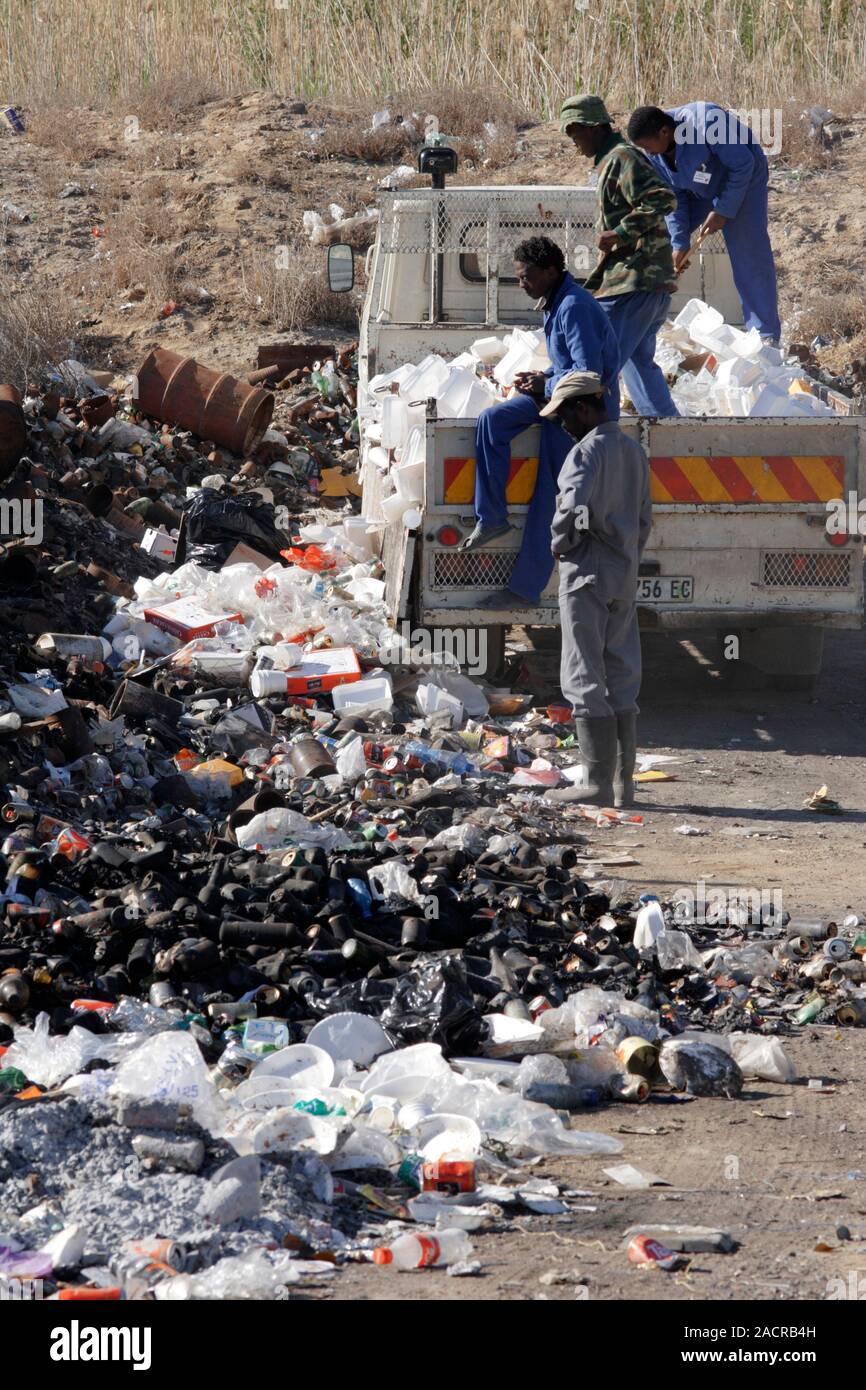 Rubbish dumping. Men dumping recycling materials at the end of a track ...