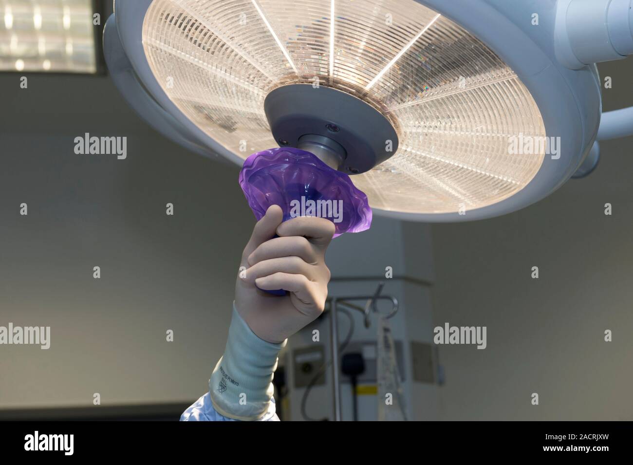 Surgical light manipulation. Surgeon's hand reaching upwards and using ...