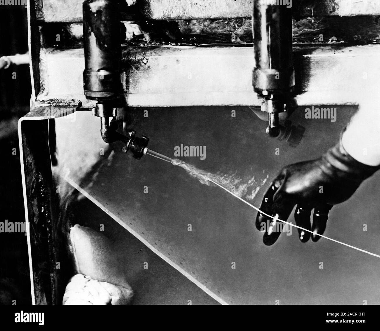 Rayon production. Gloved hand touching a strand of rayon as it is ...