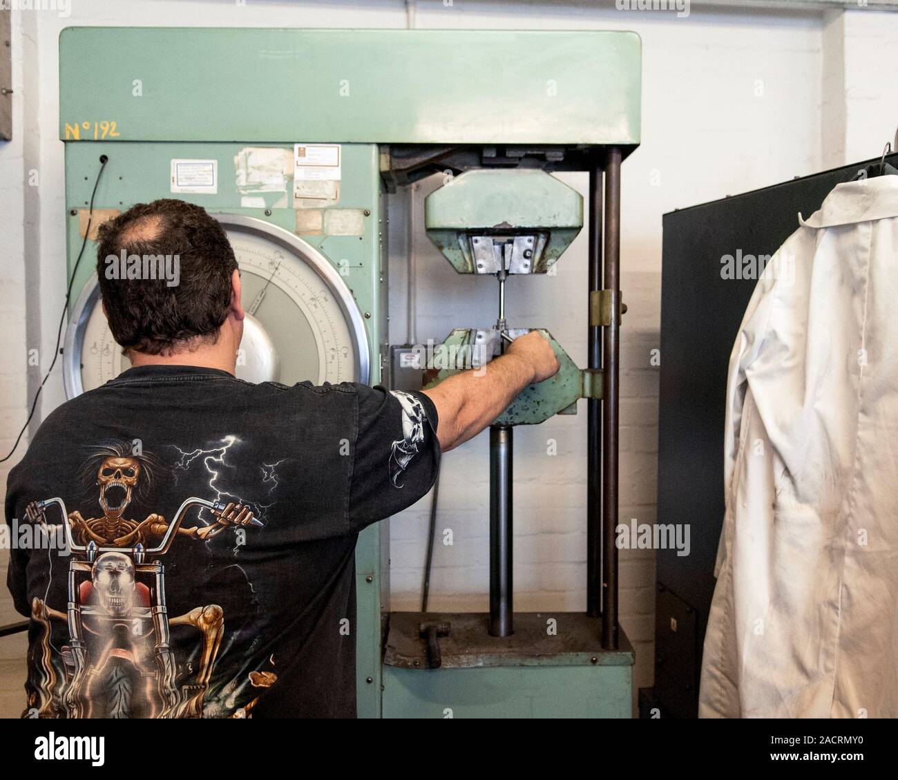 Testing strength of metal parts. Worker using a clamp and testing ...
