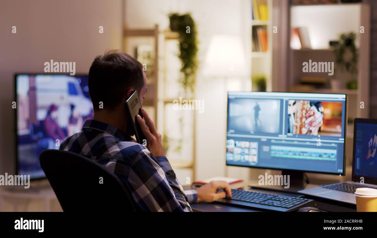 Content creator talking on the phone while working on a multimedia ...