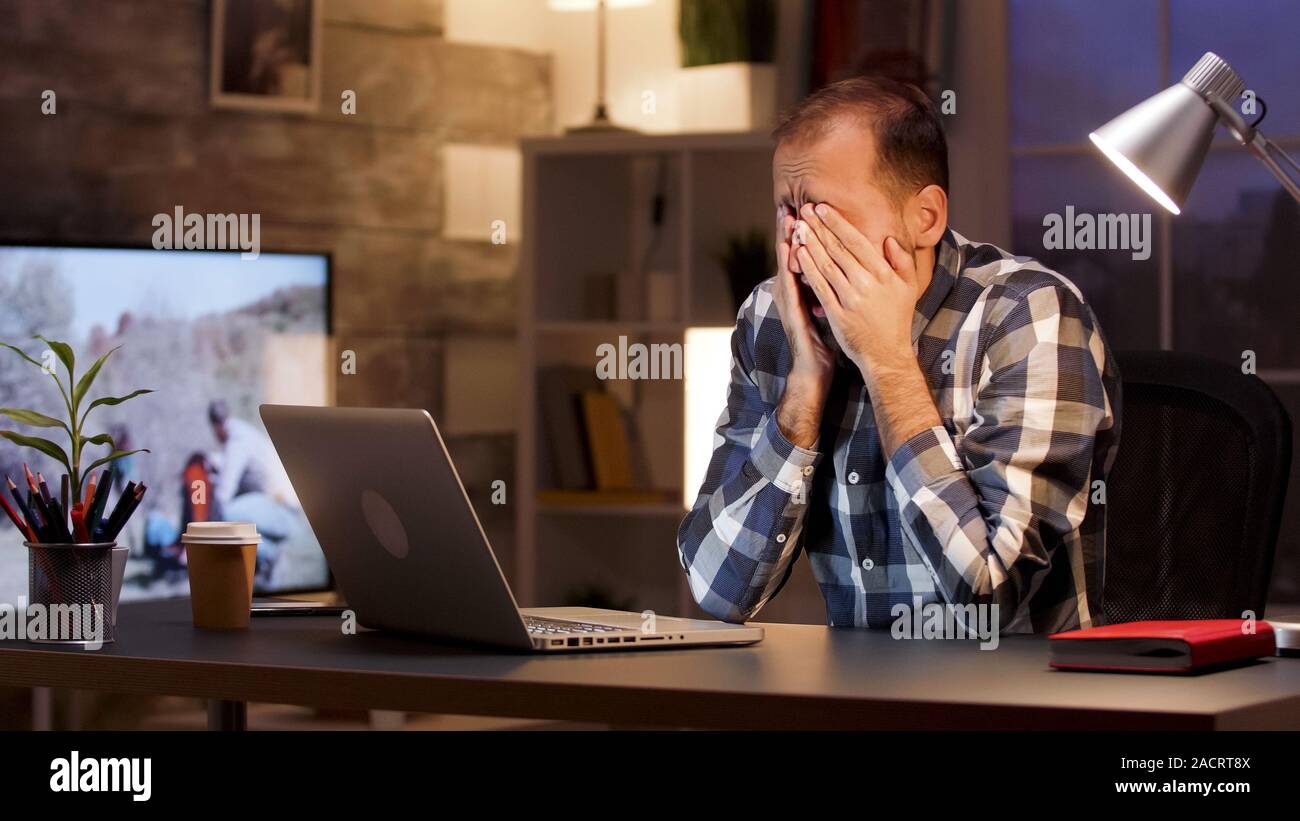 Tired businessman yawn and rubbing eyes in home office during late ...