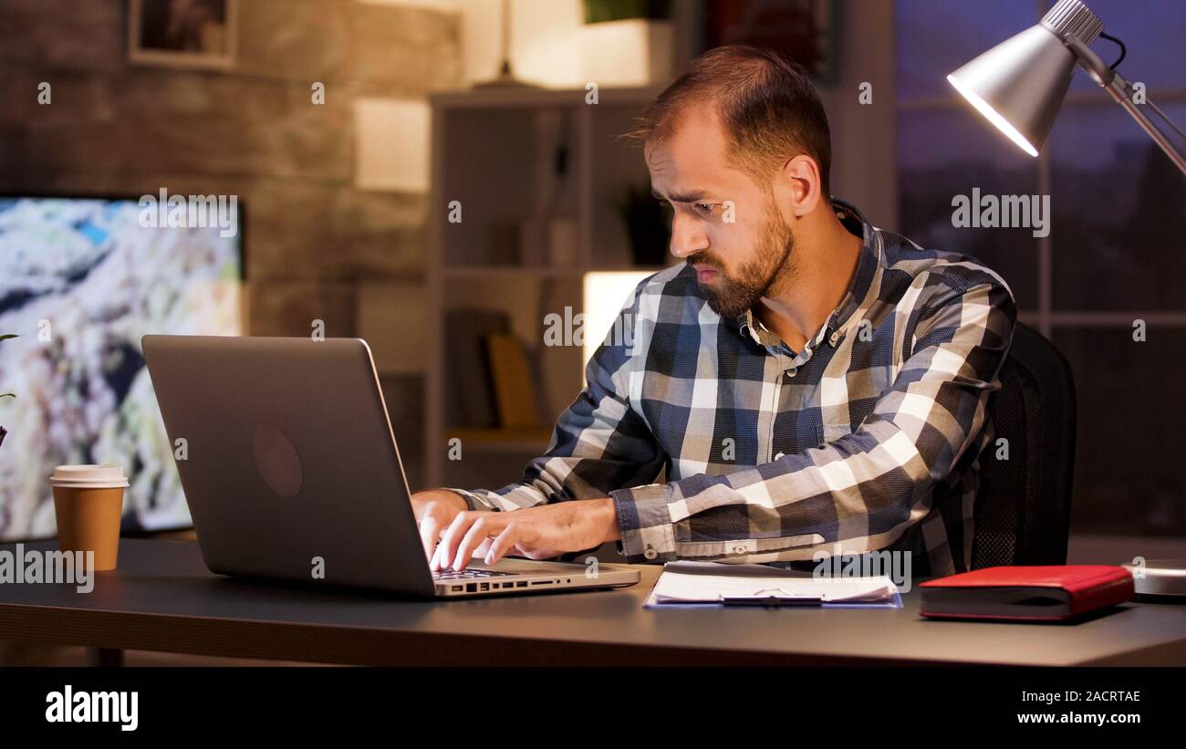 Businessman typing on laptop and searching through documents while ...