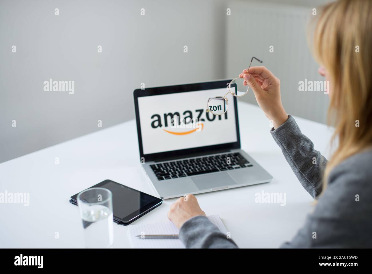 Young woman using laptop with Amazon logo in the screen seeting at the ...
