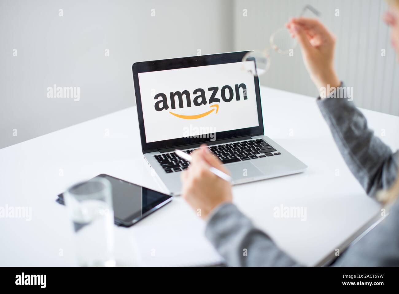 Young woman using laptop with Amazon logo in the screen seeting at the ...