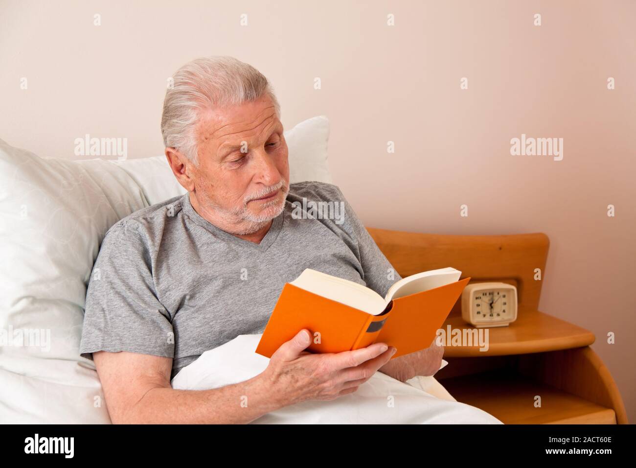 Senior in an old people's home reading a book Stock Photo - Alamy