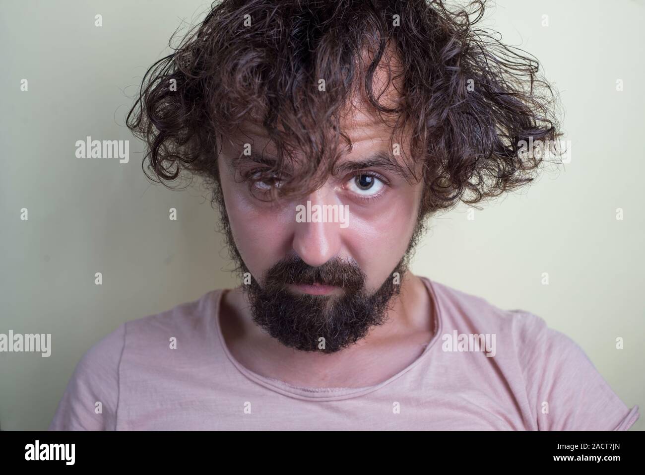 portrait of a young guy with long dirty hair on his head. Looks at the ...