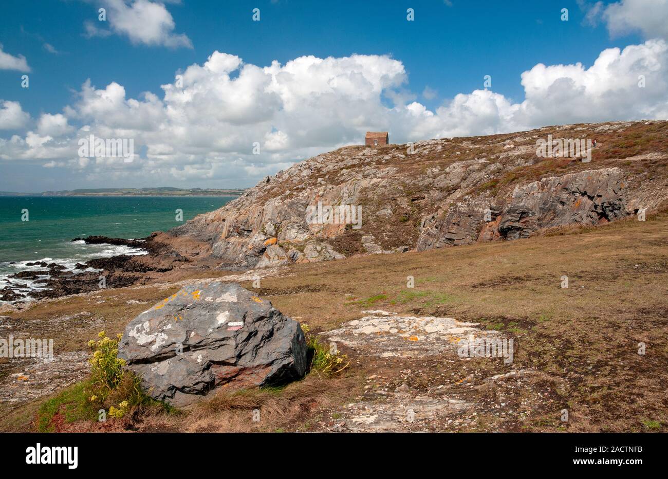 GR coastal path and stone house at the Pointe de Tal ar Grip, bay of ...