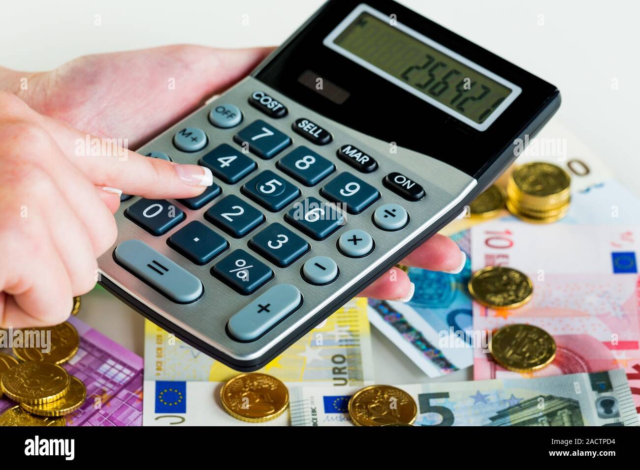 Hand with calculator and money Stock Photo - Alamy