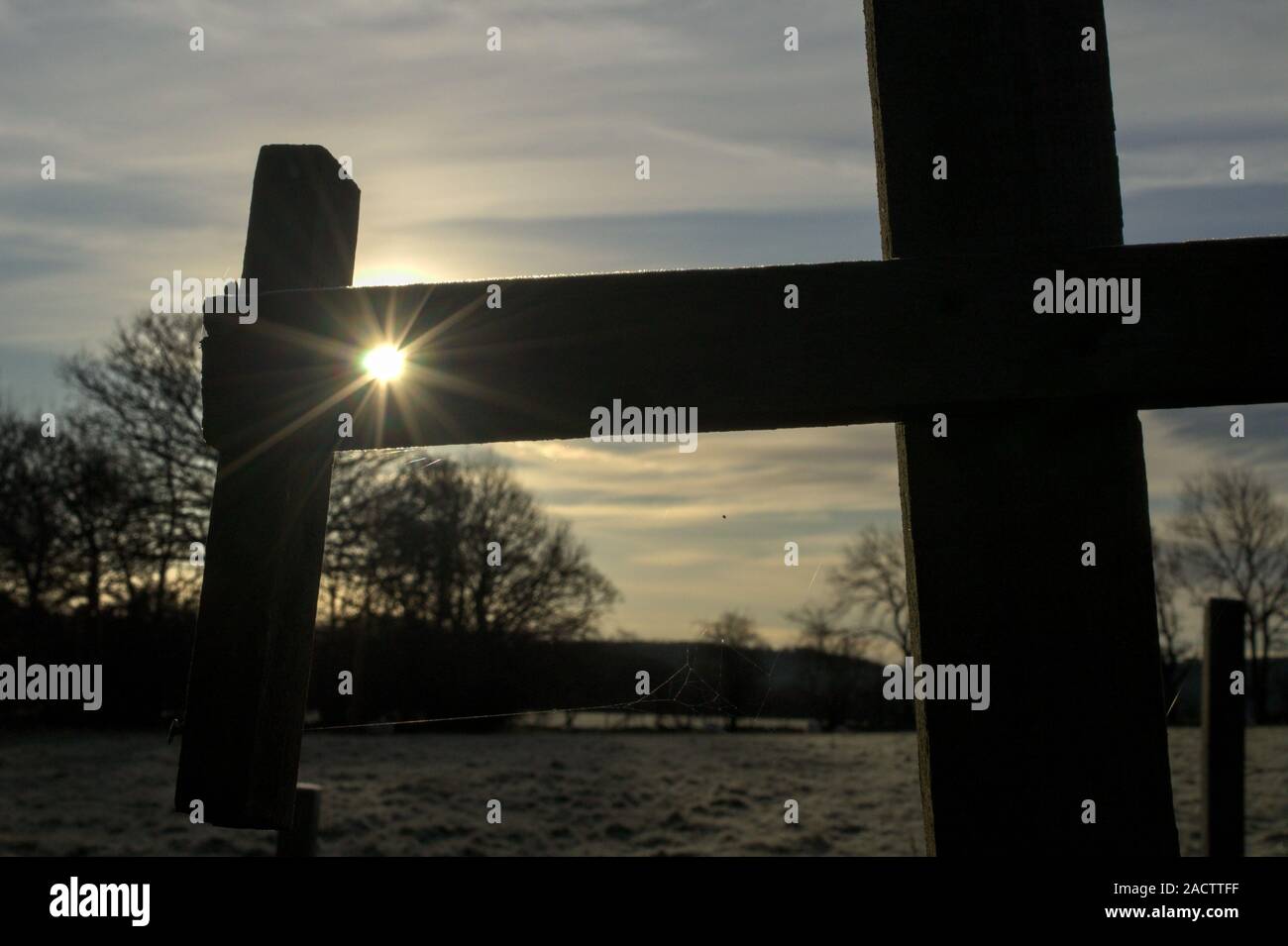UK Early morning sun rising through a small hole in a wooden frame ...