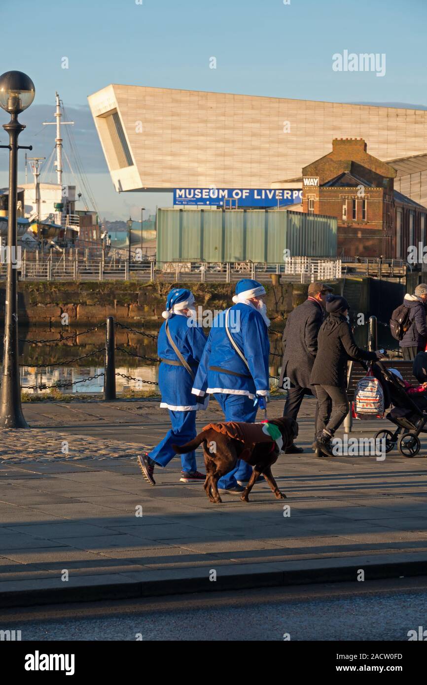 Competitors in blue Santa costumes walking with a dog as they prepare ...