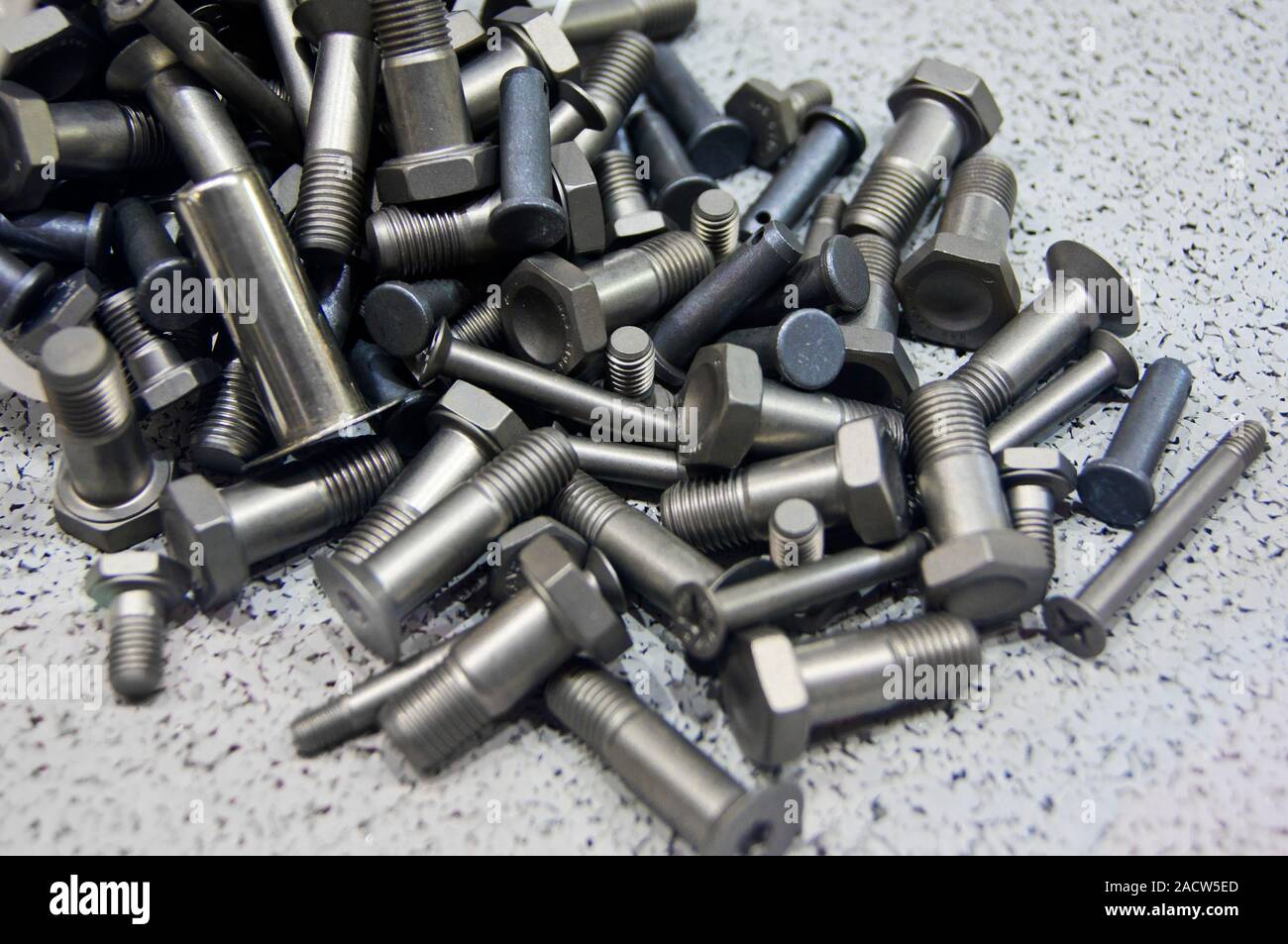 A pile of industrial bolts (with screw threads) and pins (without ...