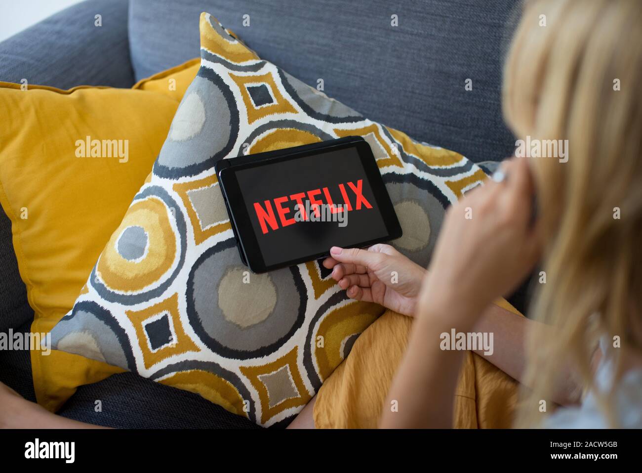 Close up on woman's hands holding tablet with Netflix logo. Young woman ...