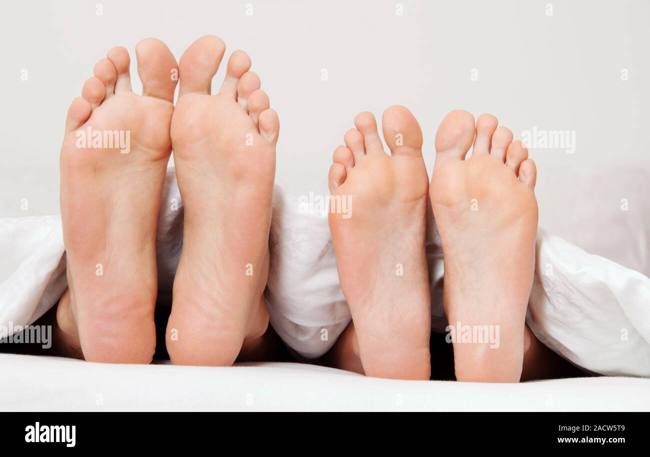 A couple's feet in bed Stock Photo - Alamy