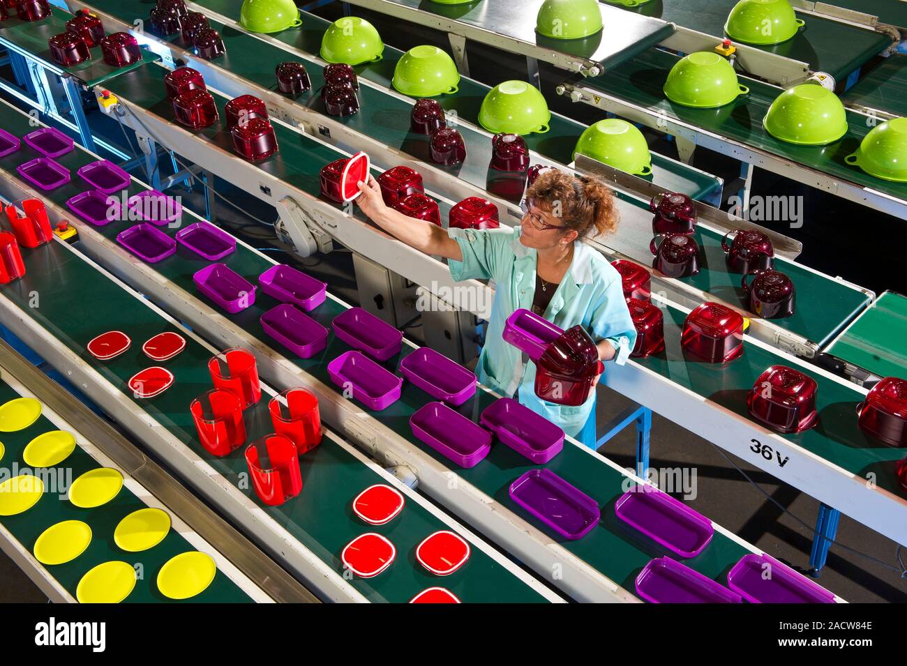 Tupperware factory. Worker checking finished products in a factory that ...