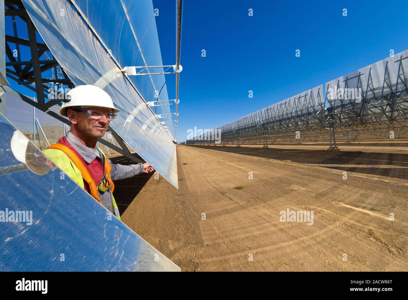 Parabolic trough solar power plant. Worker in the parabolic mirror ...