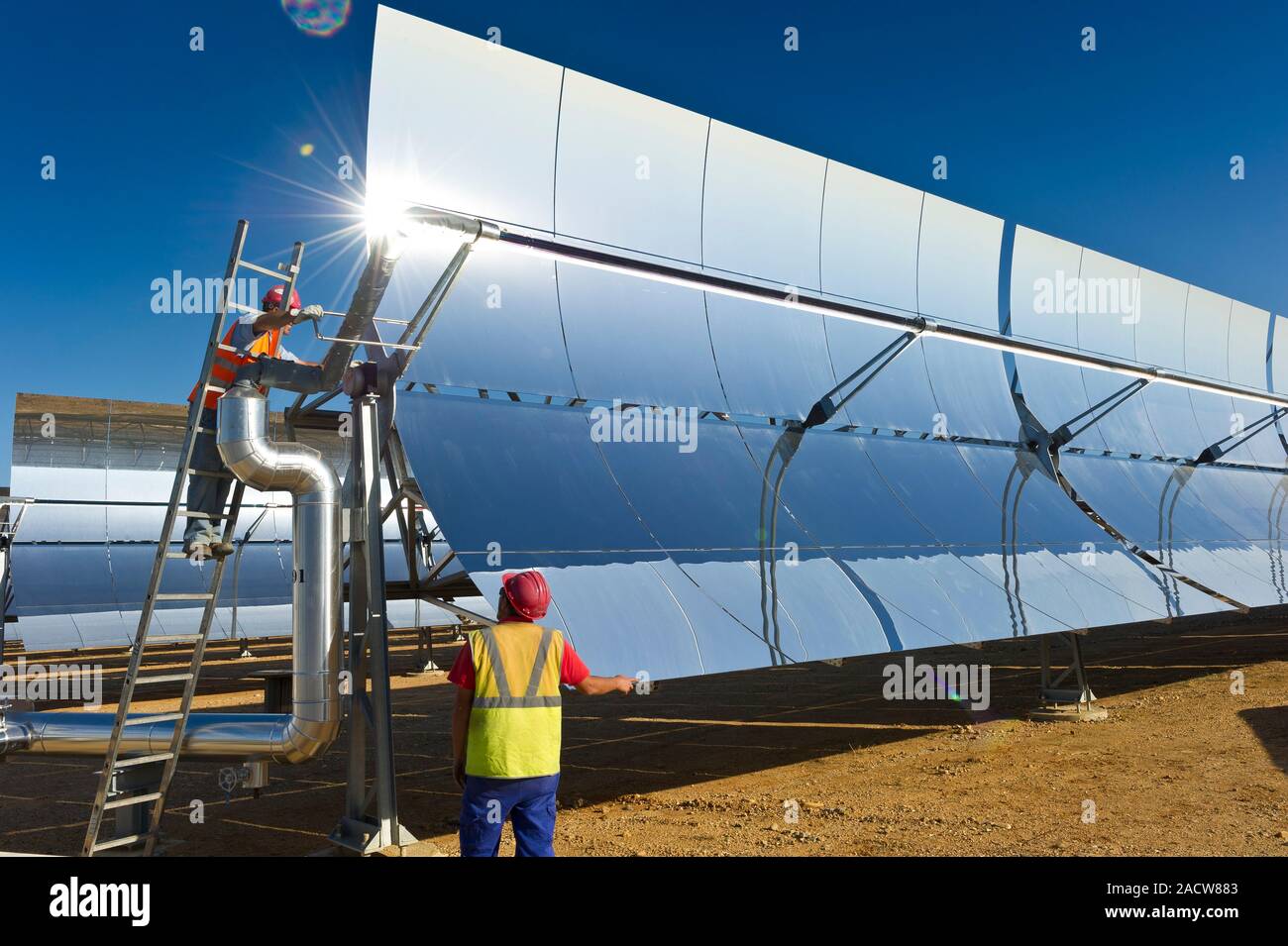 Parabolic trough solar power plant. men working on the parabolic mirror ...