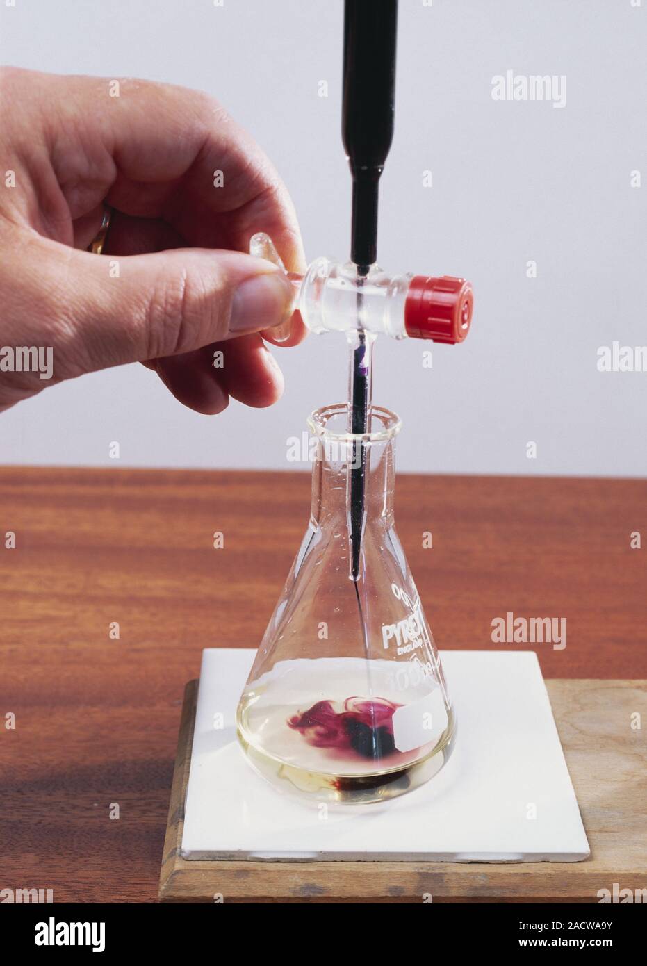 Titration. Hand adjusting a burette tap to control the flow of ...