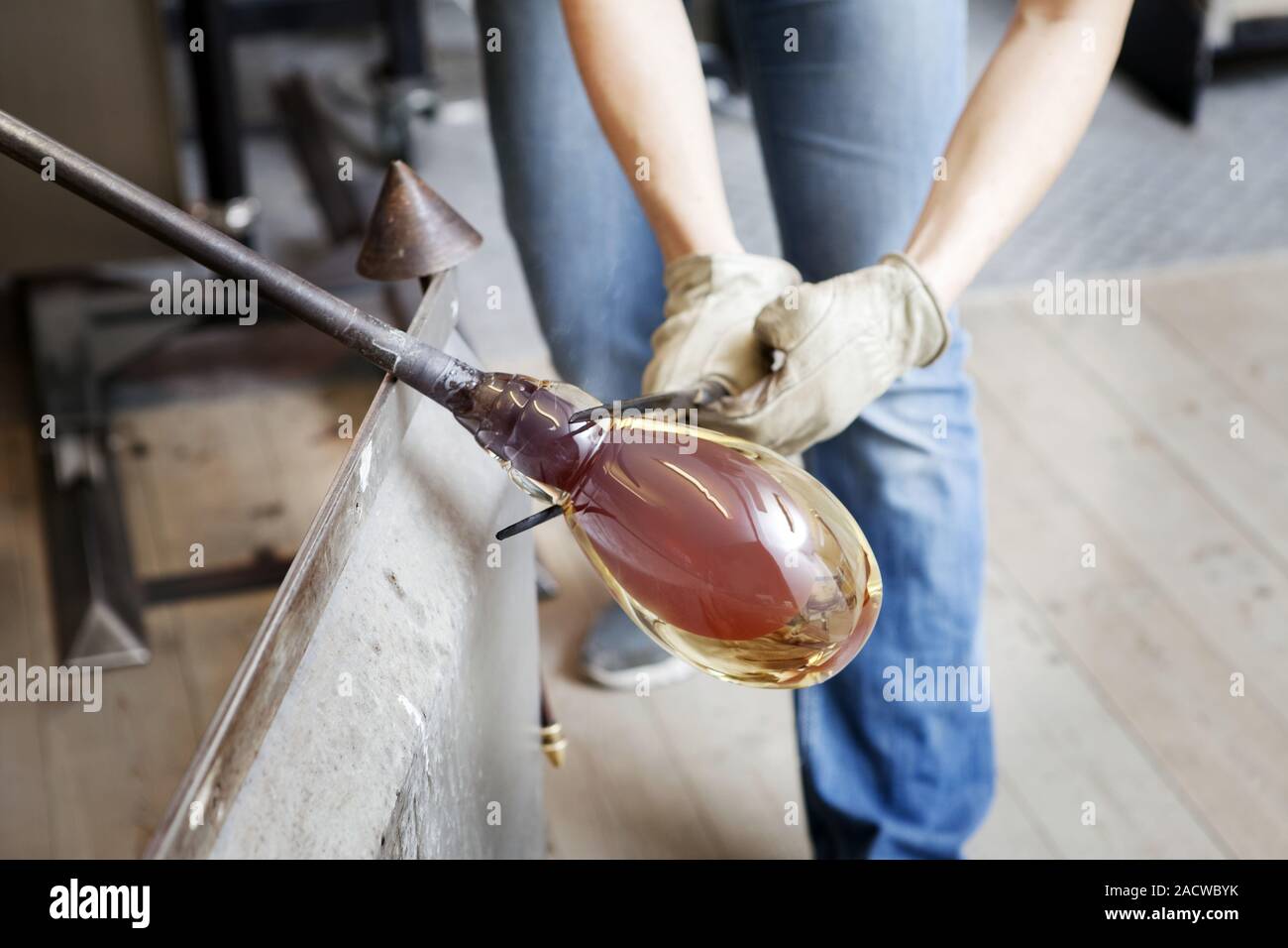 Glassblower at work. Close-up of a glassblower's assistant making a ...