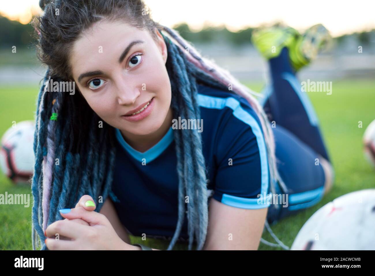 portrait of a young girl with dreadlocks. In football uniform, lying on ...