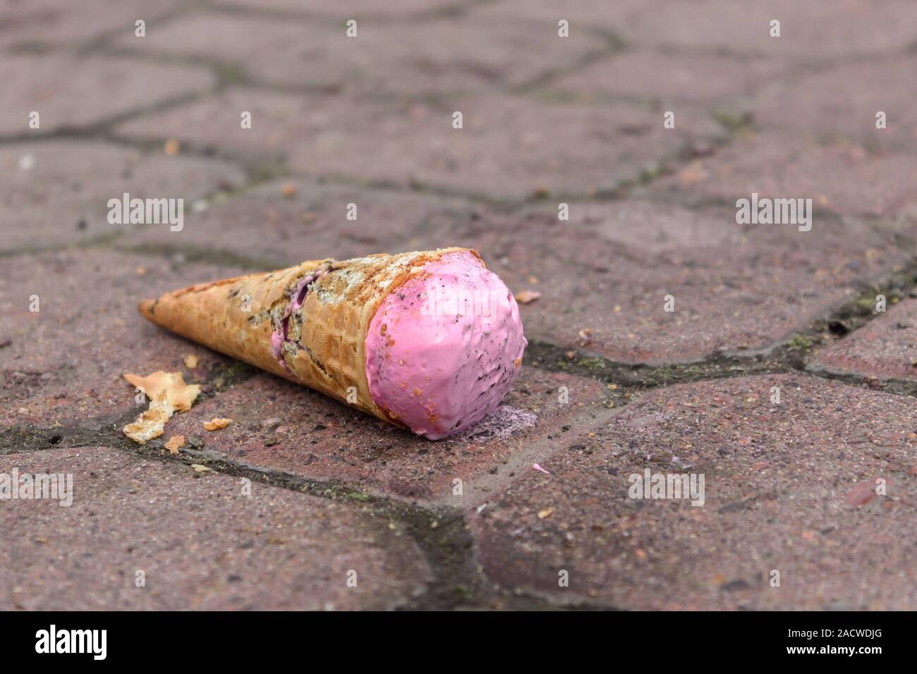 Fruit ice cream waffle cone falling on the road, melts outdoors Stock ...