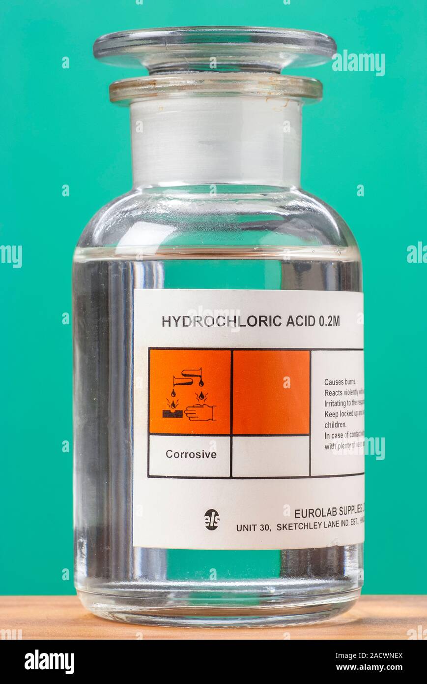 Laboratory bottle of 0.2 molar solution of hydrochloric acid, with a corrosive hazard label ...