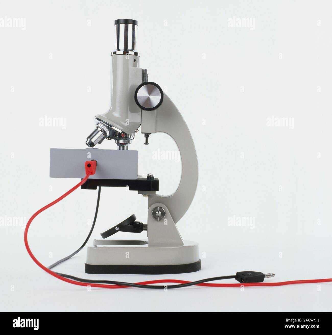 Side view of a microscope with red and black wires Stock Photo - Alamy