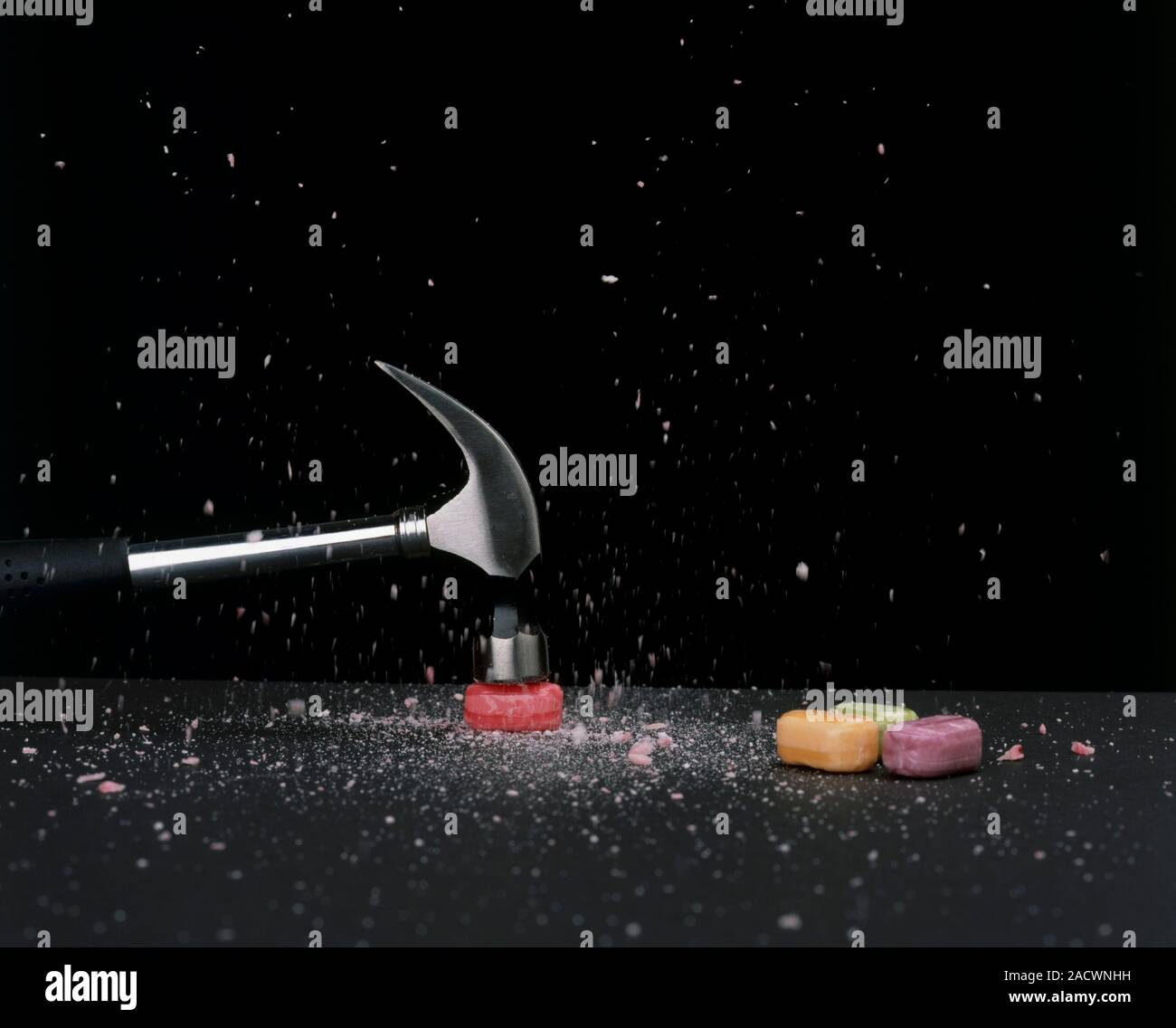 Hammer smashing a boiled sweet on surface, black background Stock Photo ...