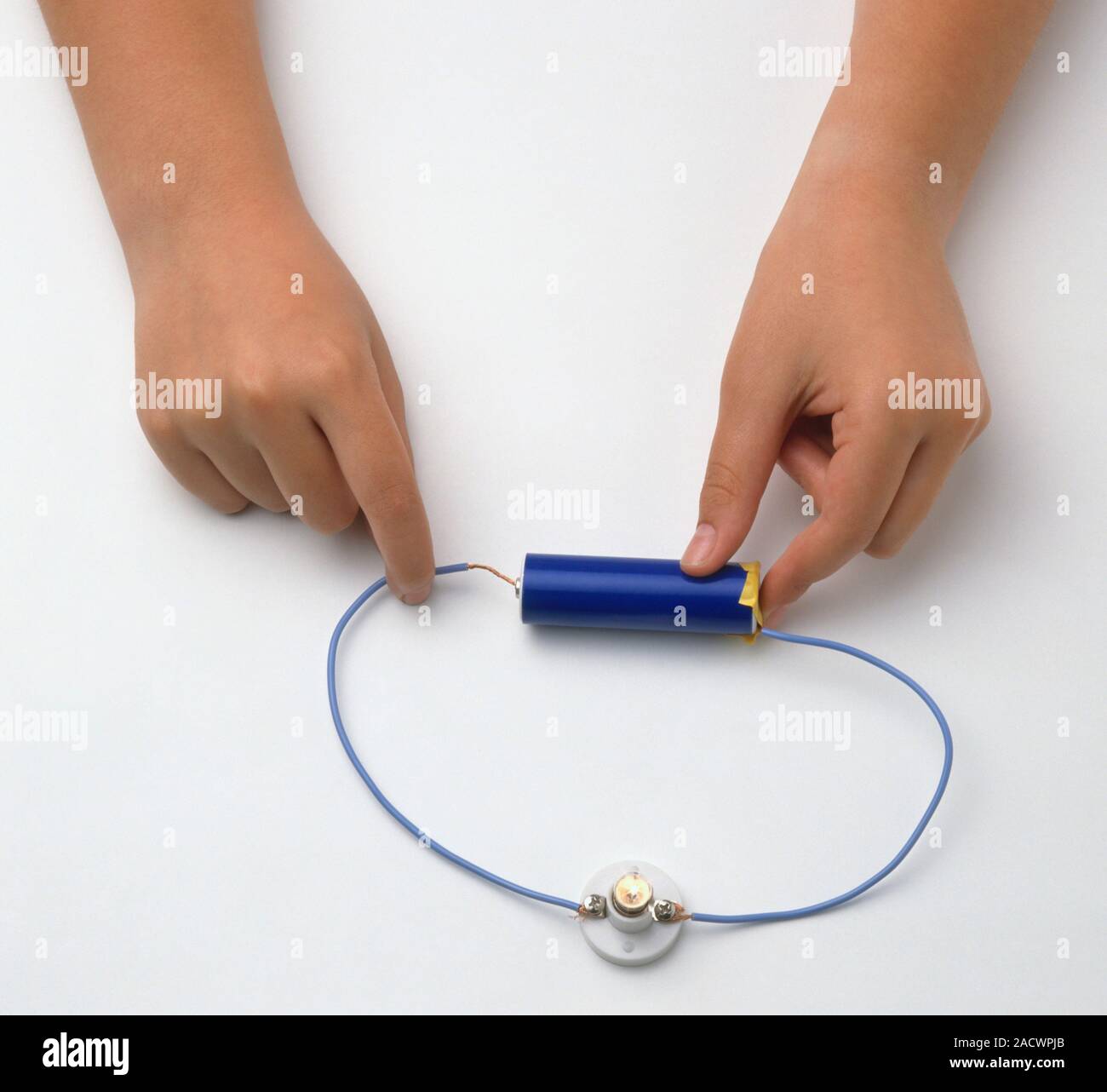 Girl's hands connecting wire with battery, making simple electric ...
