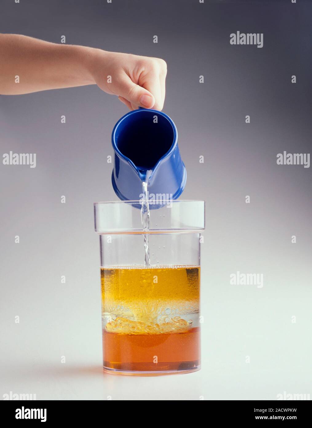 Hand pouring a jug of water into container of oil and syrup Stock Photo ...